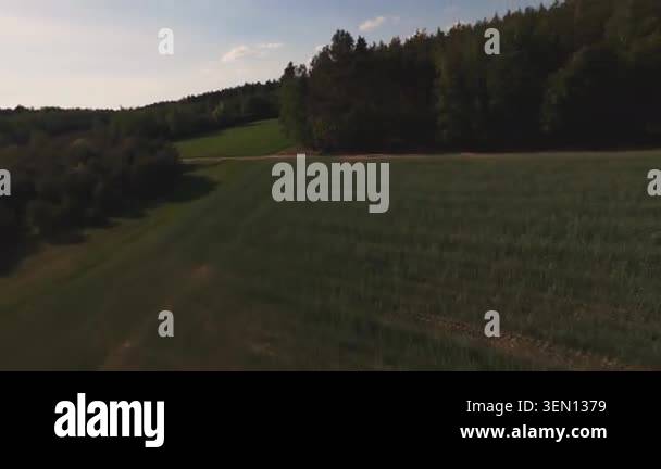 Dynamic FPV drone footage racing low over cultivated cropland with ...