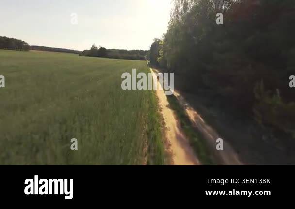 High-speed FPV drone footage skimming over green crop fields bordered ...