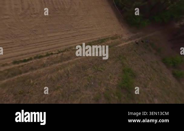 Aerial footage of cultivated farmland with distinct crop rows adjacent ...