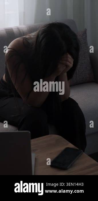 Depressed woman with head down sitting on sofa in despair at home next ...