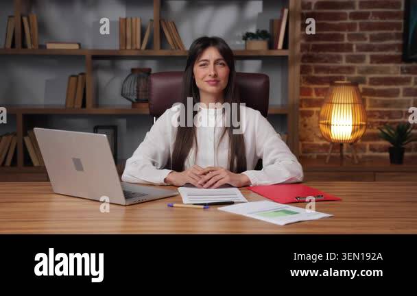 A business woman looks at the camera, smiles, and makes a stop gesture ...