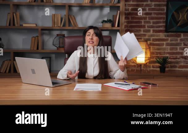A business woman expresses anger while talking to the camera and holds ...