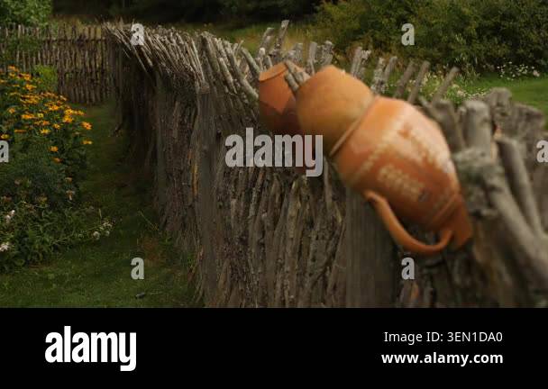 Two clay jugs hanging on a wooden fence with grass and wildflowers at ...