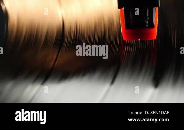 Close-up of a needle on a spinning vinyl record, capturing the grooves ...
