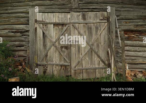 Rustic wooden gates of a farm building with grass and wildflowers at ...