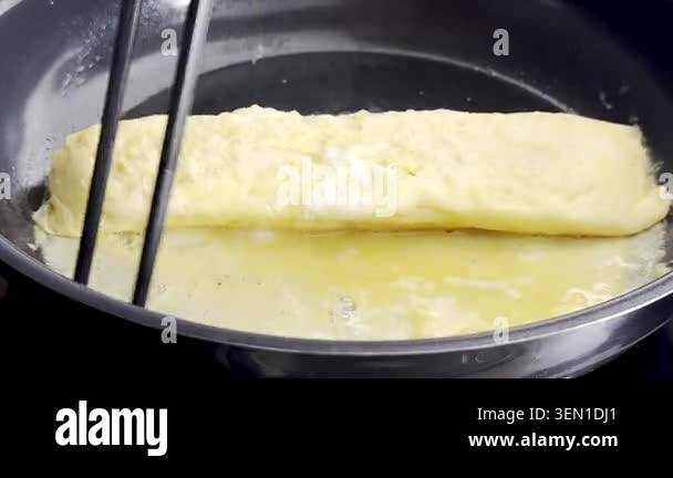 Fluffy omelette is flipped in a non-stick frying pan, highlighting the ...