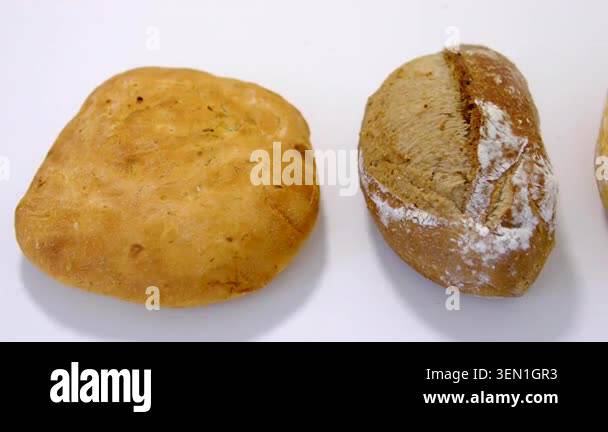 Freshly baked bread with golden crusts is displayed on a white table ...