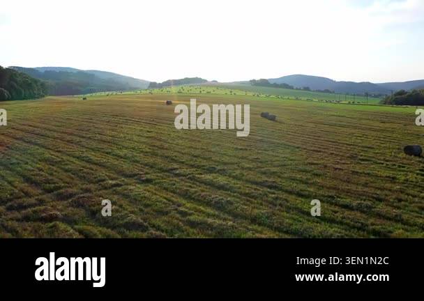Drone Flying Backward Over Harvested Field With Hay Bales and Rolling ...
