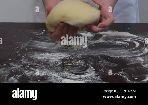 Young female hands gently knead soft golden dough on a black tabletop ...