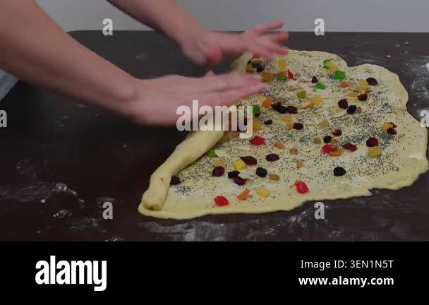 A woman carefully rolls the soft dough filled with butter, poppy seeds ...
