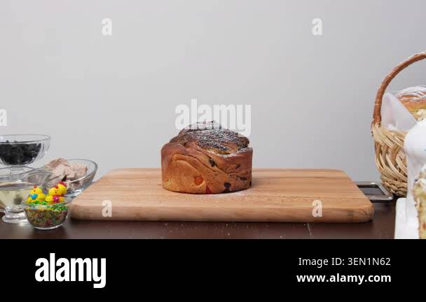 golden cruffin stands on a wooden board while a light cloud of powdered ...