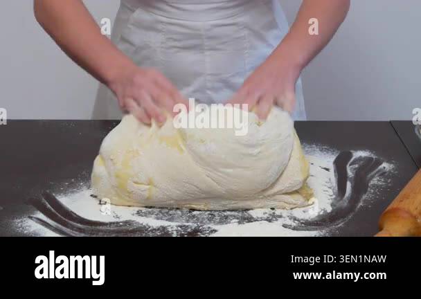 Young female hands gently knead soft golden dough on a black tabletop ...