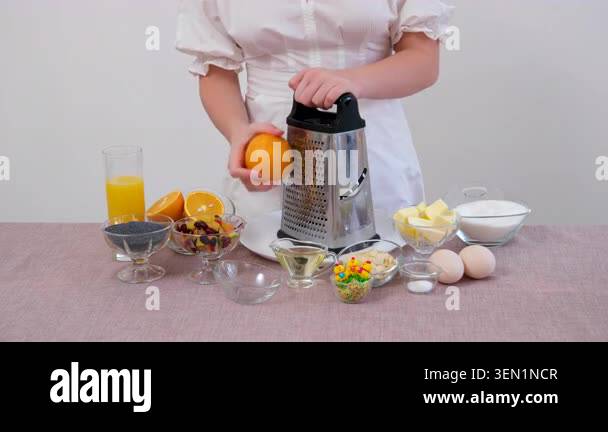 Female hands carefully grate fragrant orange zest into a bowl for sweet ...