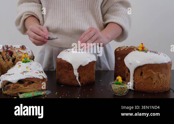 A woman coats a freshly baked panettone in glossy white icing, gently ...