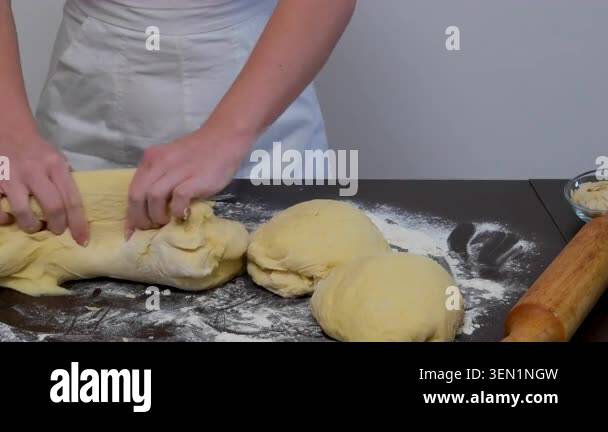 Young female hands gently knead soft golden dough on a black tabletop ...