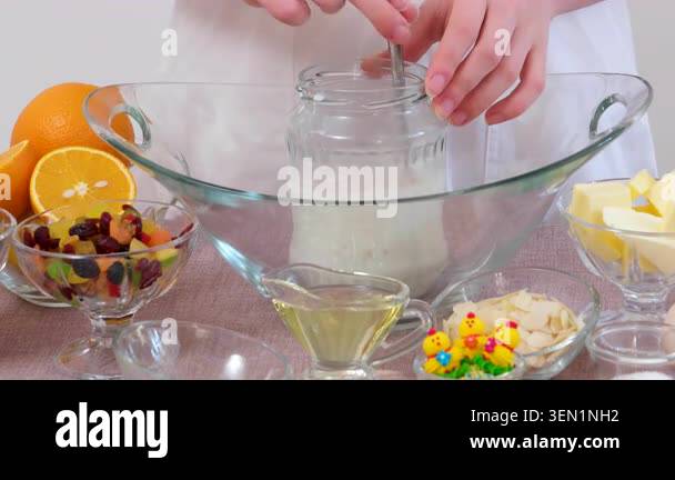 Female hands stir milk with sugar and yeast in a glass jar. Raisins ...