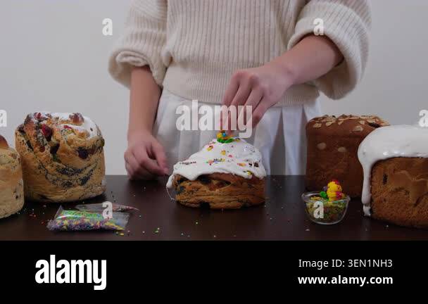A woman carefully places tiny sugar chicks on top of freshly glazed ...