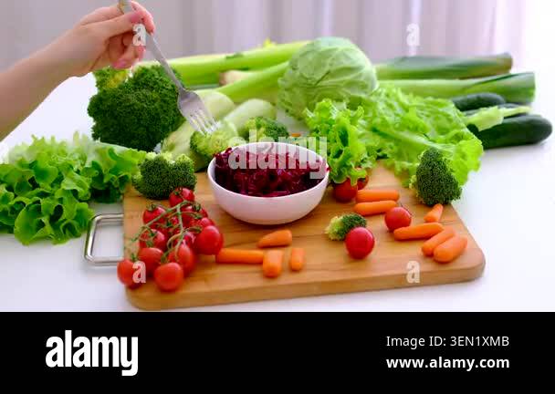 Fork picking fresh grated beetroot from white plate surrounded by ...
