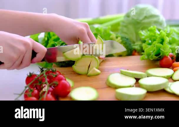 Female hands slicing young zucchini into triangle chunks on rustic ...