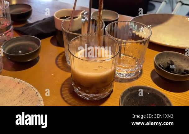 Dark sparkling cola poured into clear glass on wooden restaurant table ...