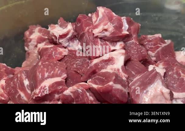 Raw pork neck cubes being placed into bowl for barbecue marinating ...