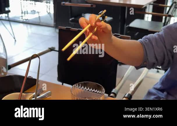 Training holder attached to chopsticks helps woman practice picking up ...