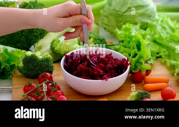 A fork lifts a portion of freshly grated boiled beetroot from a white ...