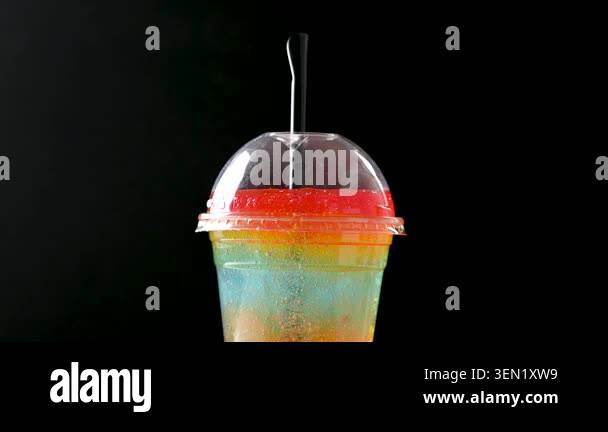Colorful slushie spinning in clear plastic cup on black background ...