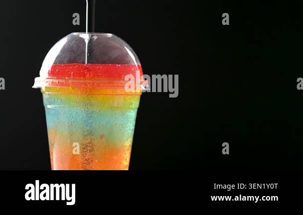 Colorful slushie spinning in clear plastic cup on black background ...