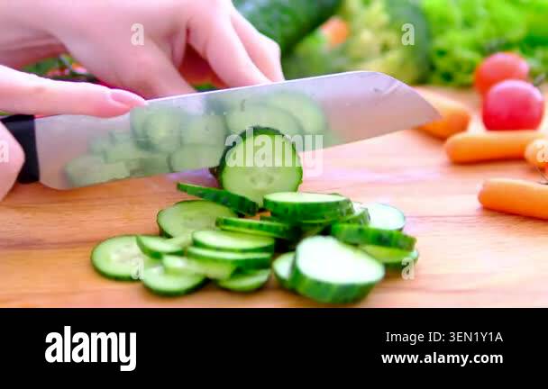 Dozens of thin cucumber slices cut on rustic wooden board beside fresh ...