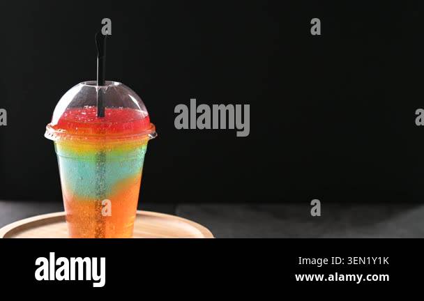 Colorful slushie spinning in clear plastic cup on black background ...