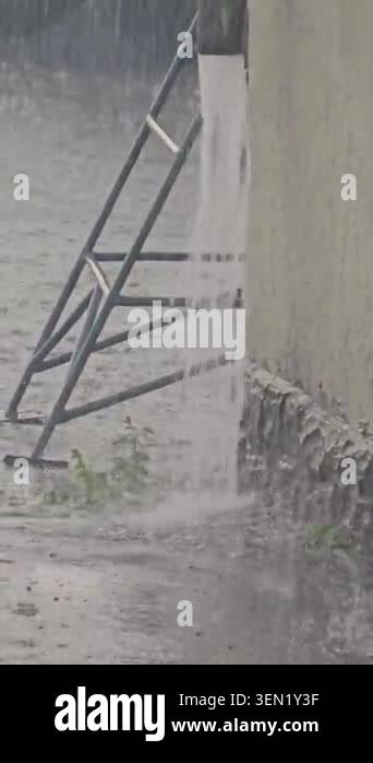 A torrential downpour sends water rushing from a roof drainage pipe ...