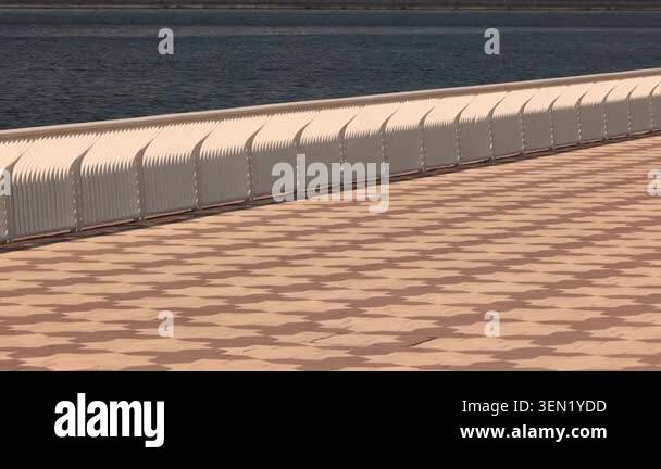 Seaside promenade with waterfront railing and paved walkway along ocean ...