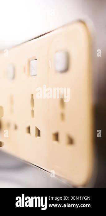 Power adapter plug connecting into electrical wall outlet close detail ...