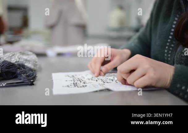 A fashion designer working at a desk painting ideas while focusing on ...