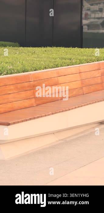 Contemporary city seating area with wooden bench and landscaped lawn ...