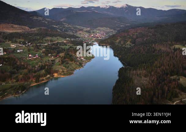Aerial drone view following Colibita Lake as it winds between forested ...