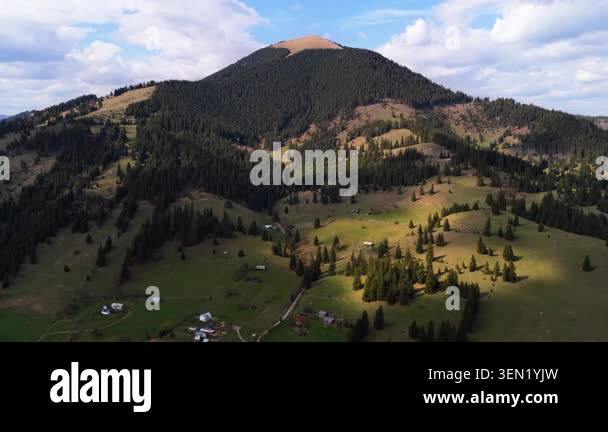 Aerial drone view over rolling hills covered with forests and open ...