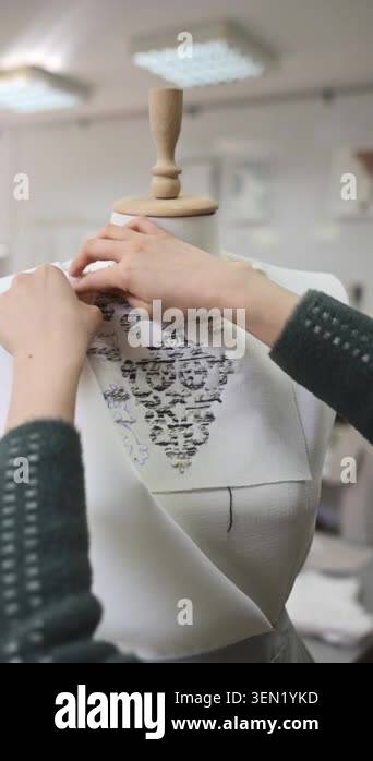 Hands carefully adjusting fabric on a dress form, securing material ...