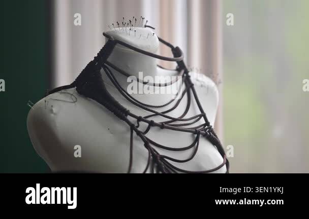 Close up of a person adjusting cords or fabric on a dress form ...