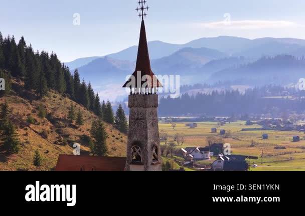 Aerial drone view of a tall wooden church tower rising above a scenic ...