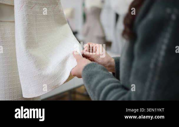 Hands carefully adjusting fabric on a dress form, securing material ...