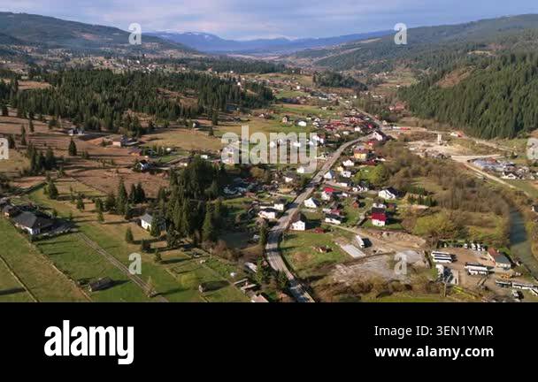 Aerial drone view of a winding river cutting through a rural settlement ...