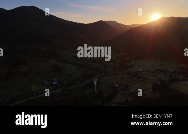 Aerial drone view down a valley with a road and scattered houses ...