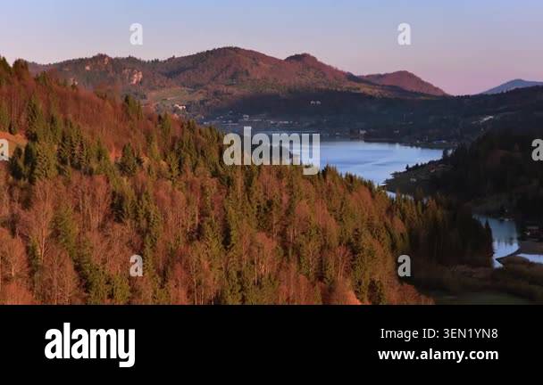 Aerial drone view of Colibita lake surrounded by dense forest and hills ...