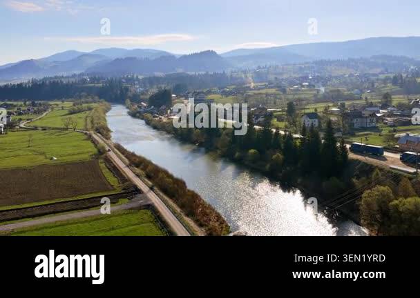 Aerial drone view of a river flowing alongside a rural road near Vatra ...
