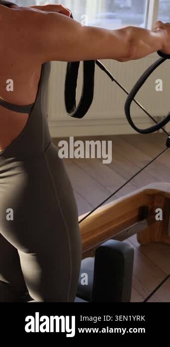 Woman training back and legs on Pilates reformer machine in modern ...