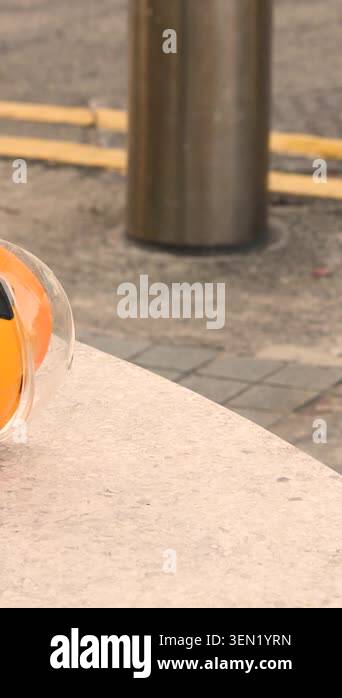 Orange construction hard hat resting on concrete surface at building ...