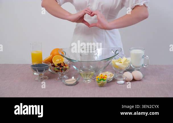A girl dressed in white forms a heart with her hands near milk, raisins ...
