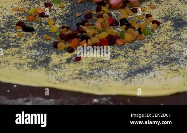 A young woman sprinkles sweet raisins and colorful dried fruits over a ...